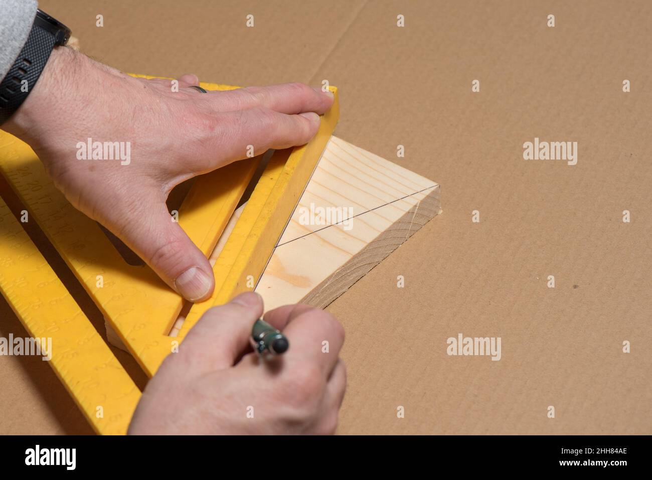 Carpenter using a pencil and old square marking a diagonal line on a ...