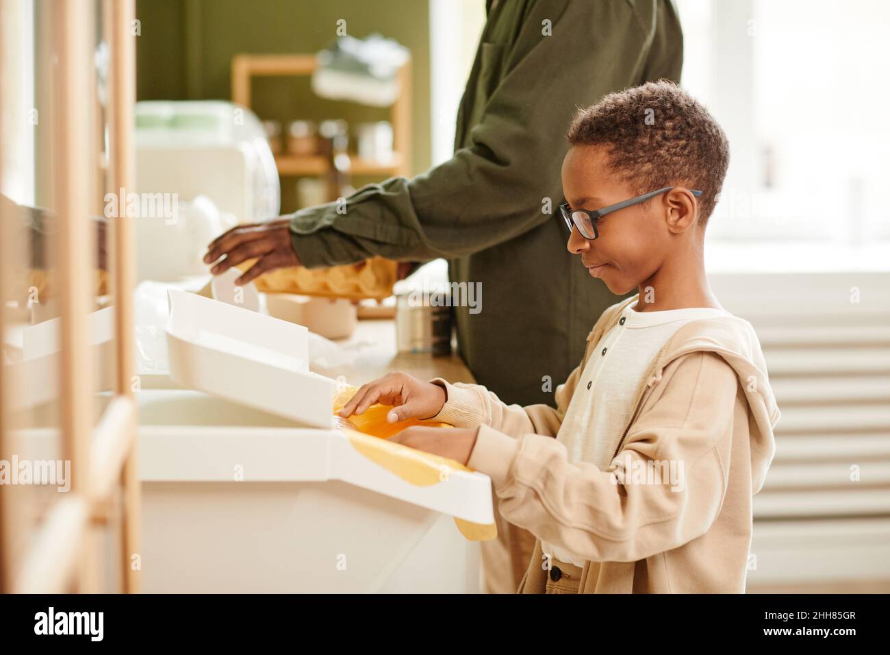 Side view portrait of teenage boy putting household waste in recycling ...