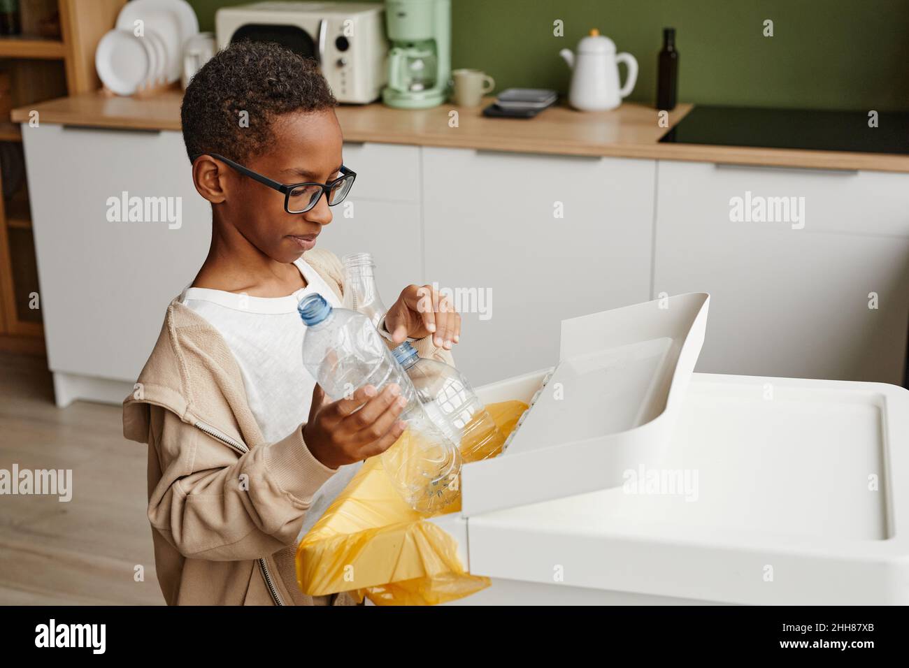 Side view portrait of African-American boy putting plastic bottles in ...