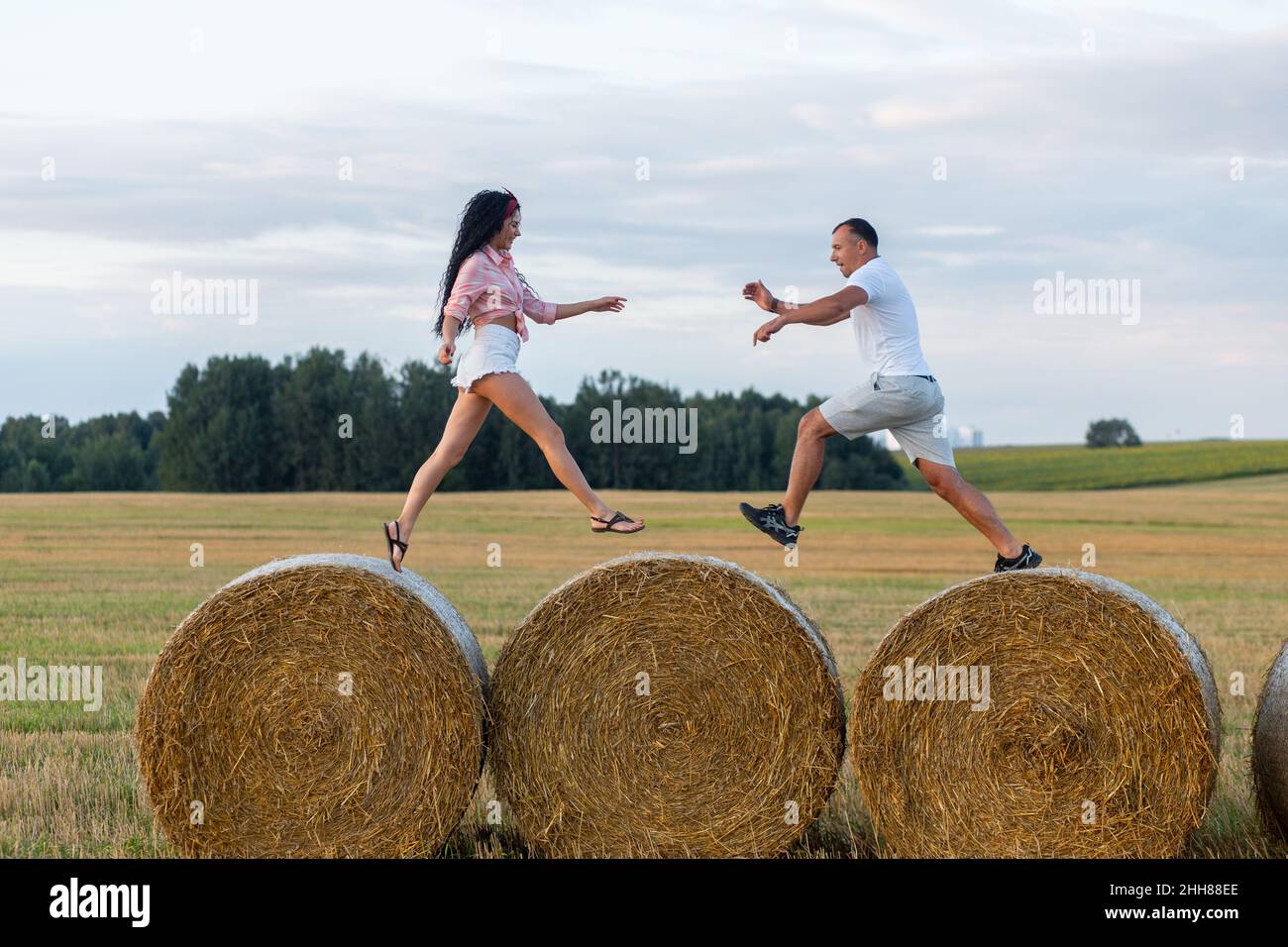 Loving couple in a field on rolls of straw. Young man and woman having ...