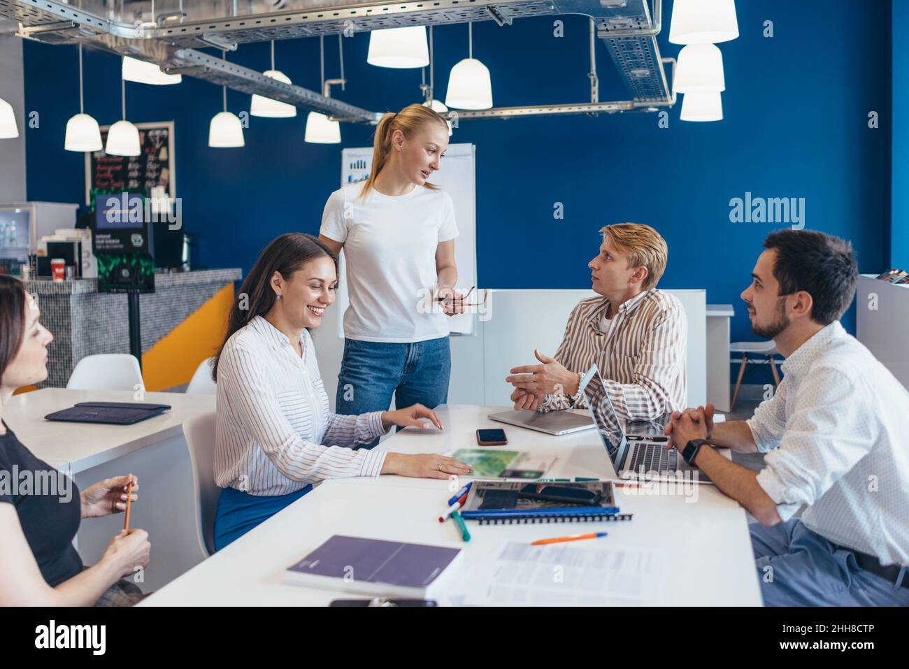 Employees in the office gathered around the desk Stock Photo - Alamy