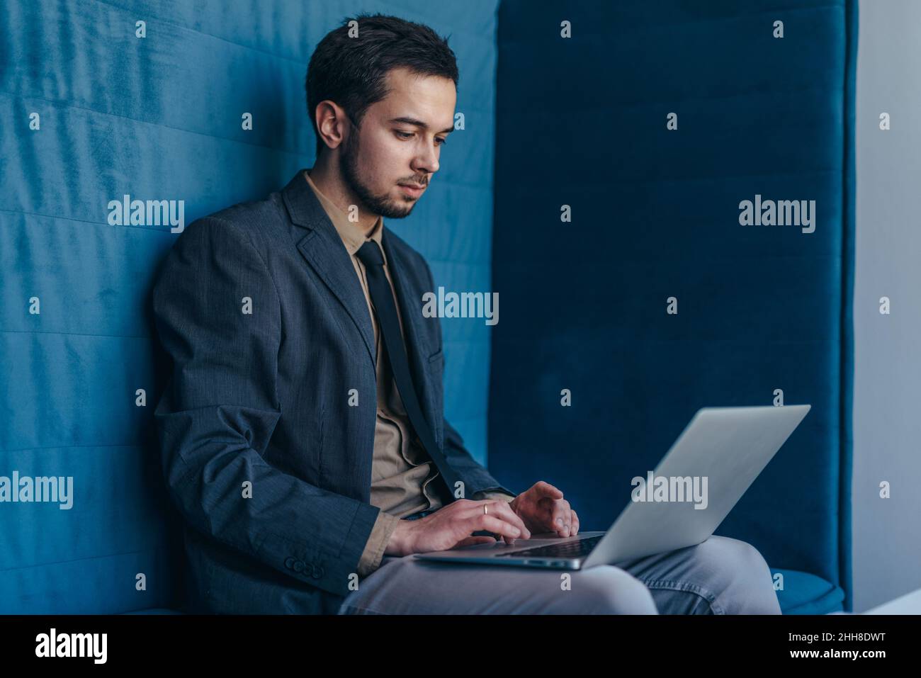 Portrait of young businessman working on laptop while sitting alone in an office cubicle Stock ...