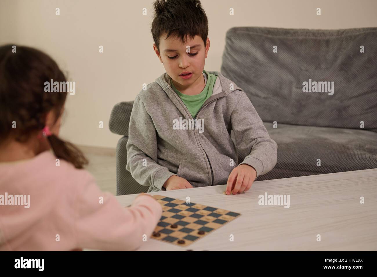 Cute little girl enjoying intellectual board game with her older ...