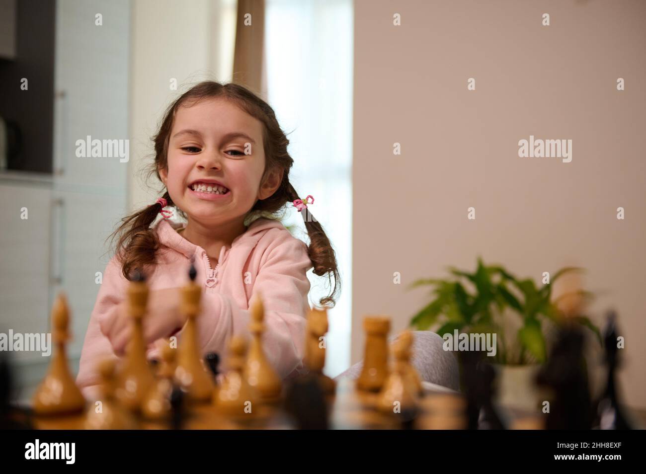 Adorable 4 years old little girl playing chess game at home. Smart ...