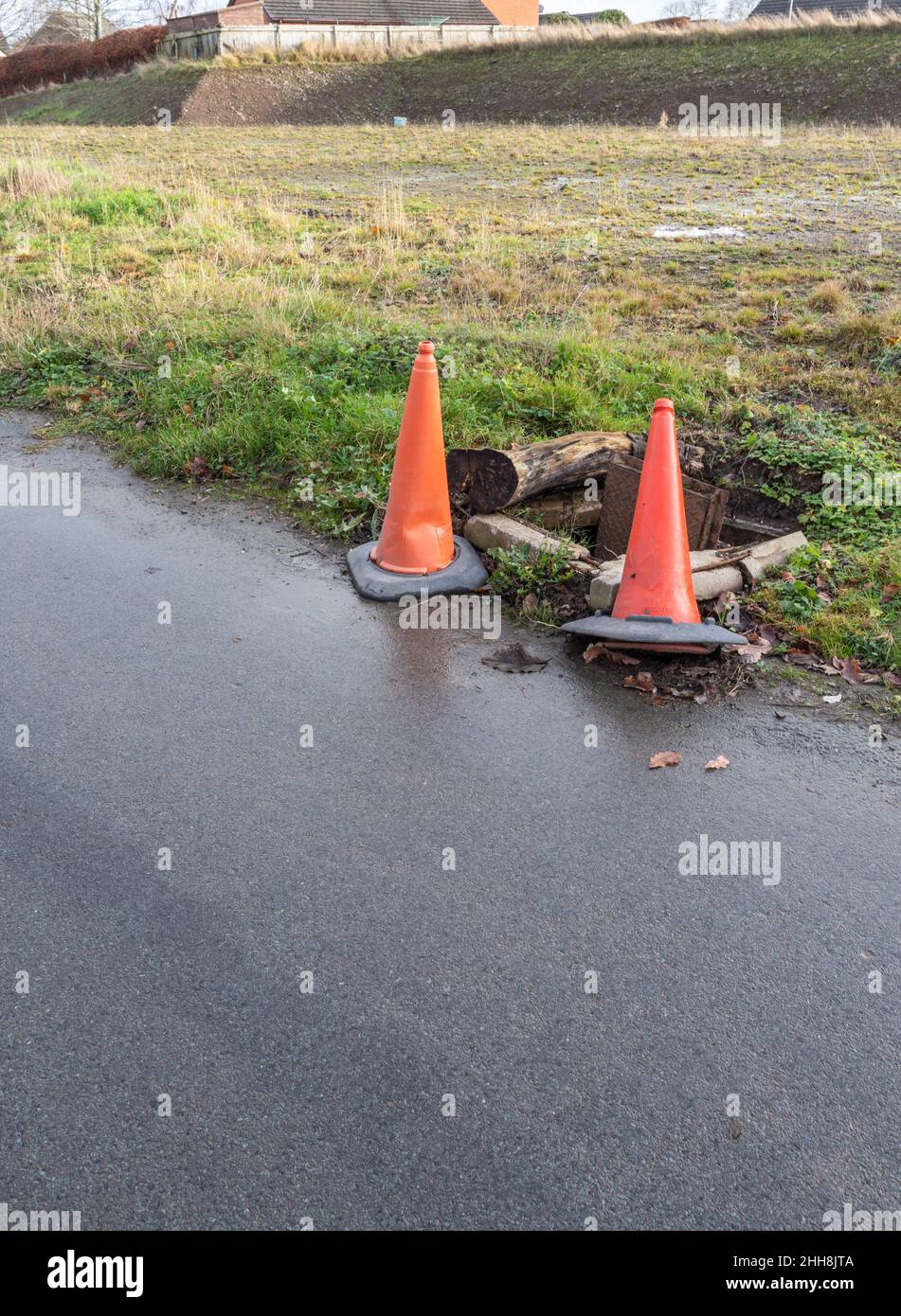 Cones by collapsed utility manhole at side of country road Stock Photo ...