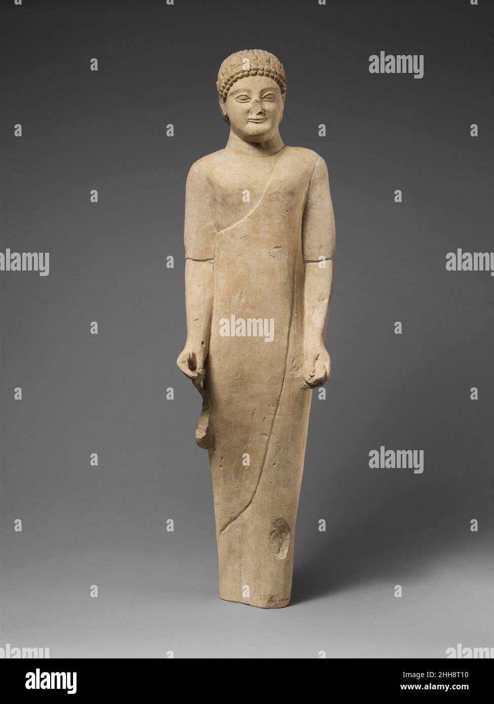 Limestone statuette of a beardless male votary with a wreath of leaves ...