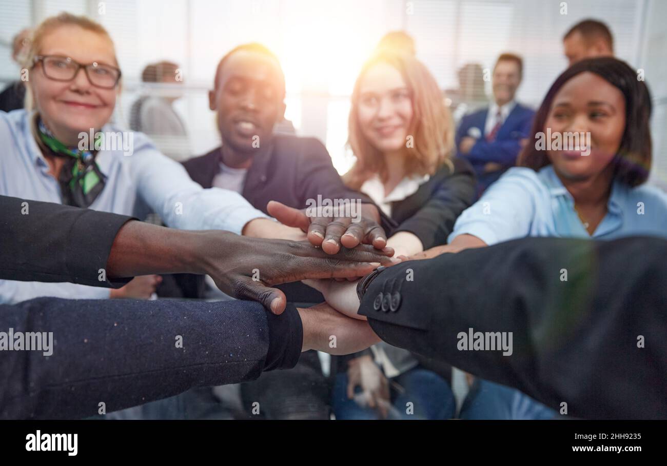 group of diverse employees joining their palms over the desktop ...