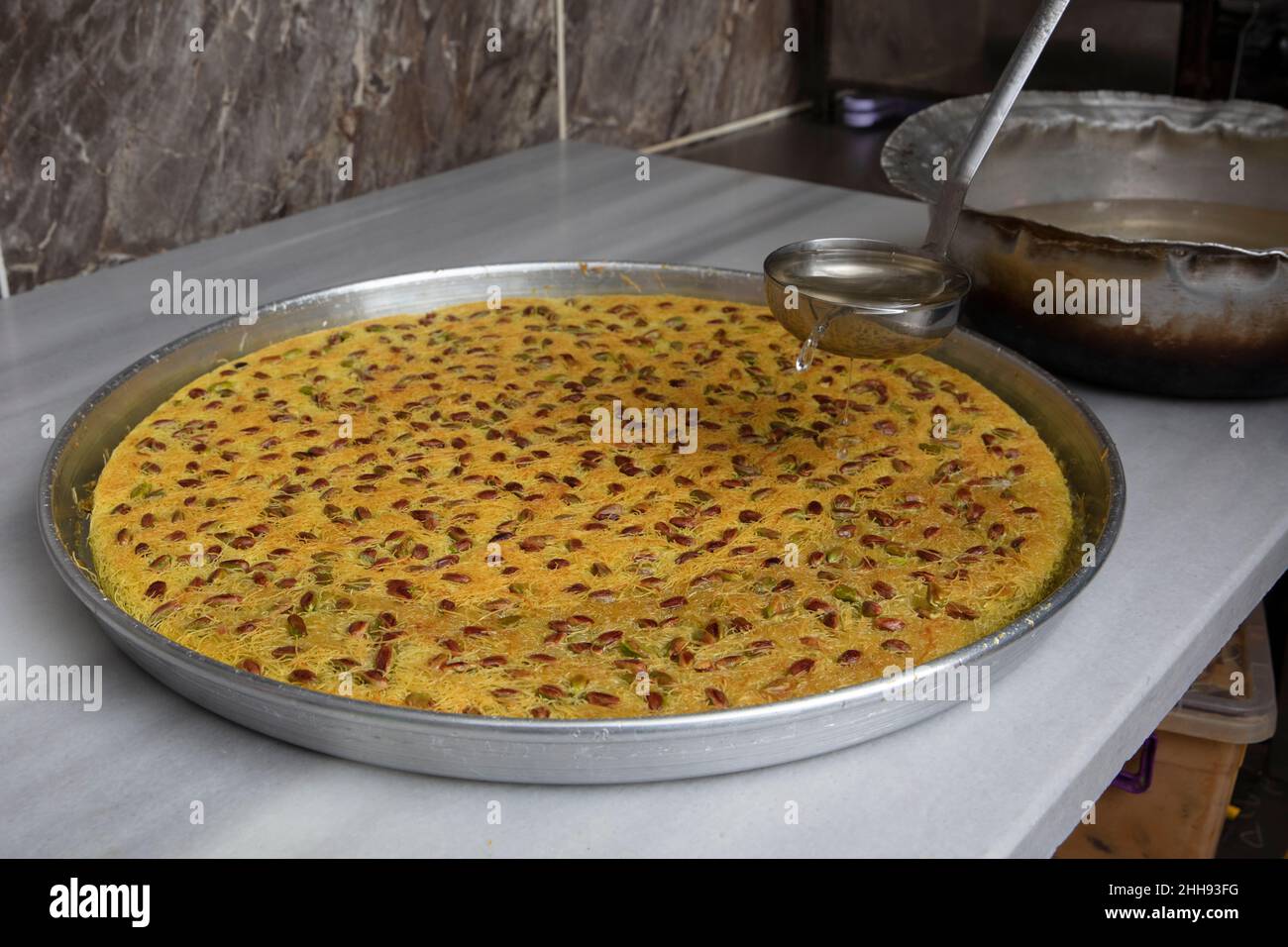 Kadayif dessert with pistachio on a tray. In the kadaif workshop, the ...