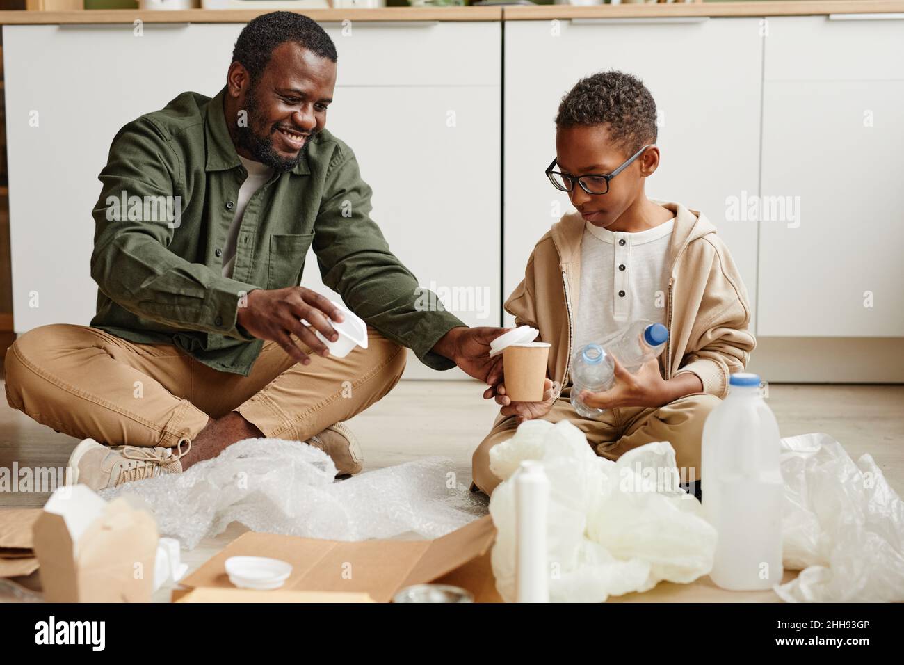 Full length portrait of happy African-American father and son sorting ...