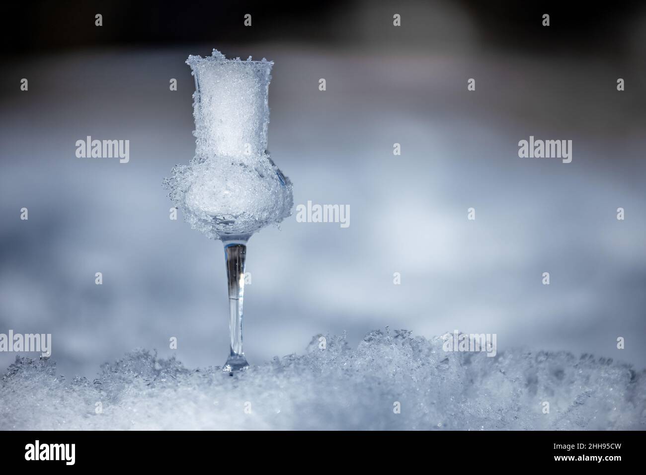 Bokeh picture of a flavored Grappa (Schnapps) glass filled with snow in ...