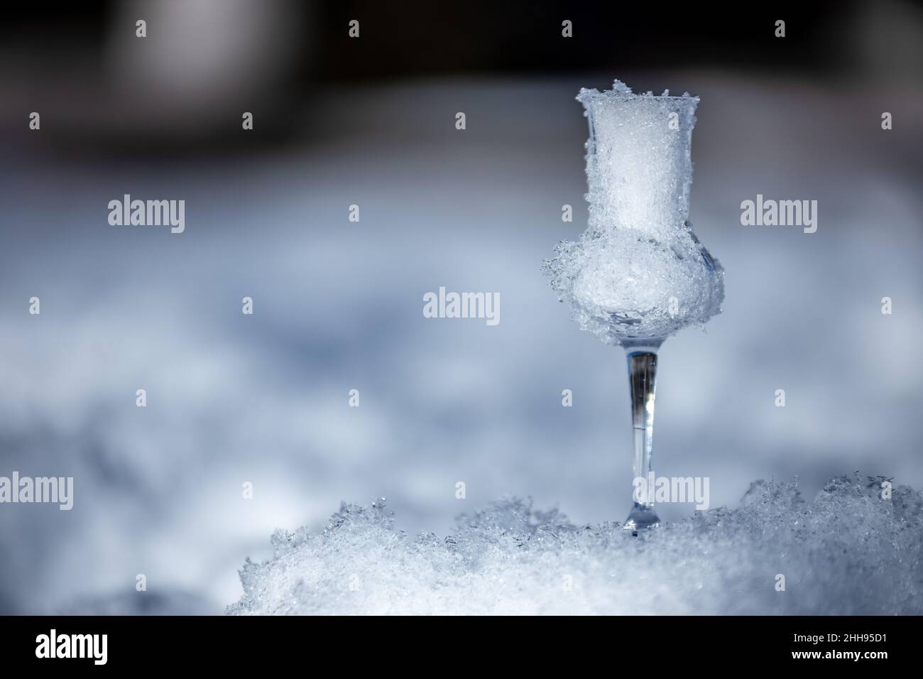 Bokeh picture of a flavored Grappa (Schnapps) glass filled with snow in ...