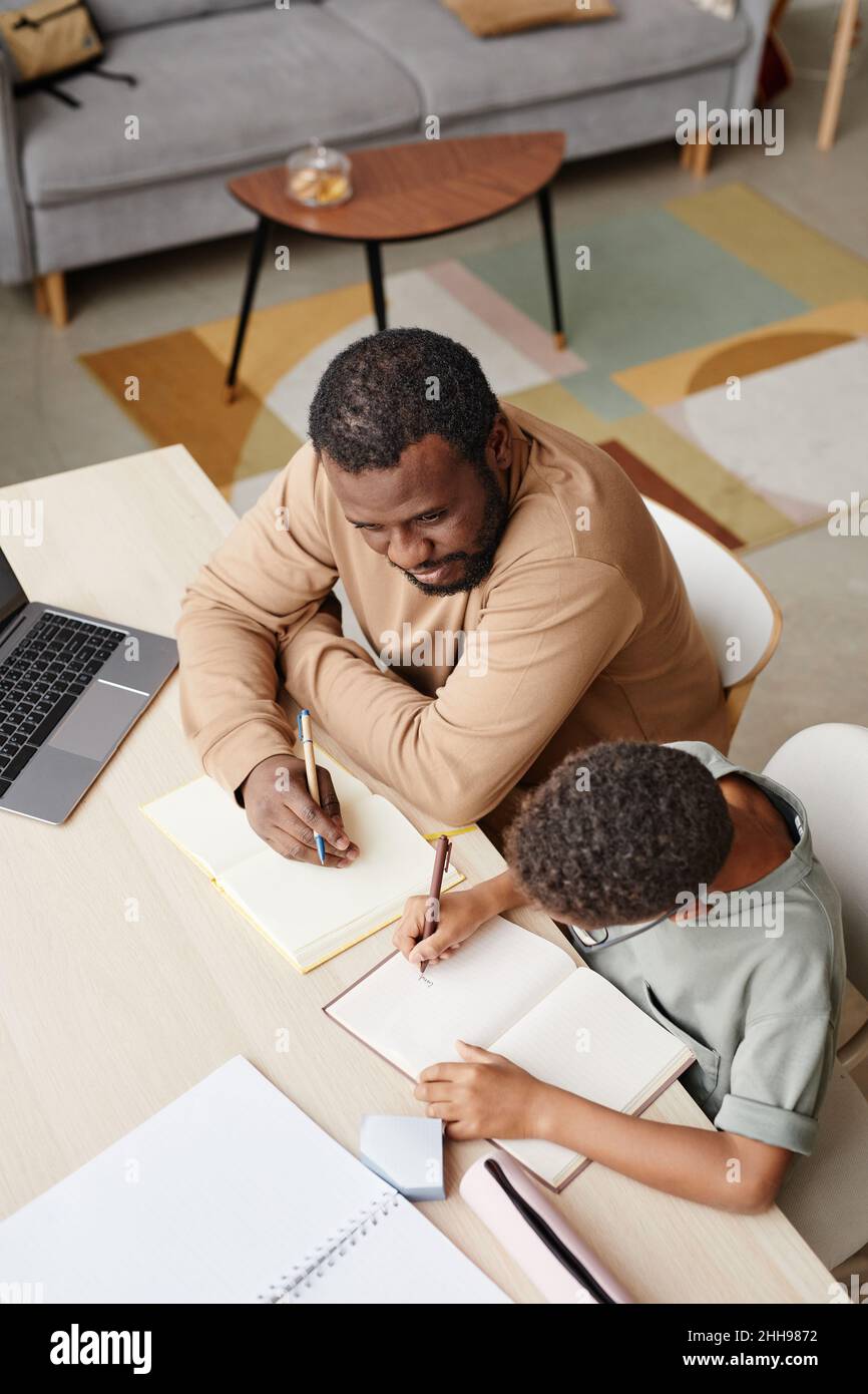High angle portrait of caring father helping son with homework while ...