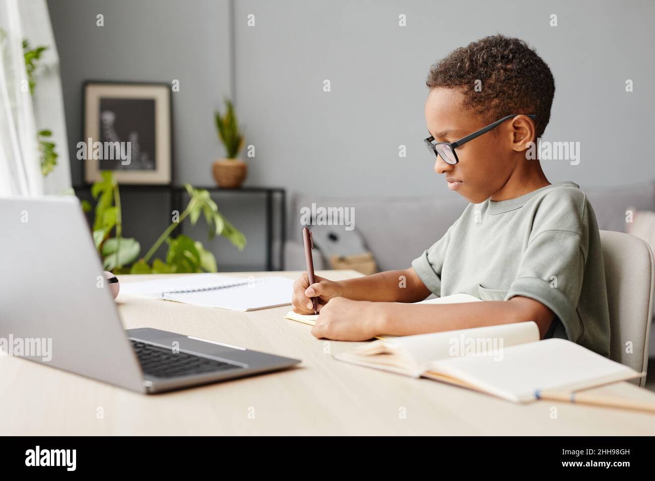 Side view portrait of African-American boy studying at home with laptop ...