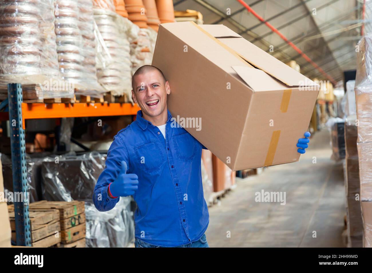 Positive warehouse worker carrying pasteboard box Stock Photo - Alamy