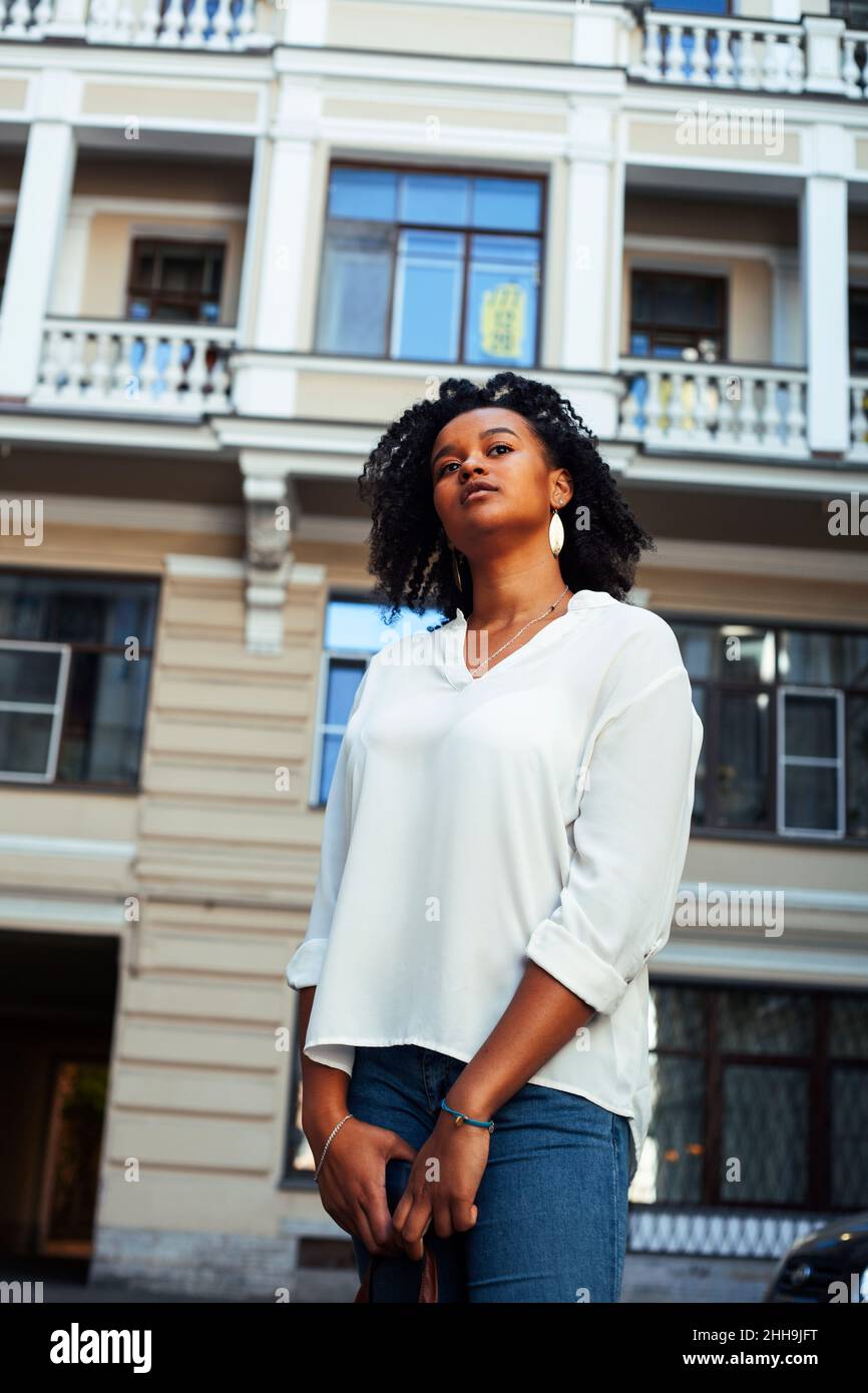 young pretty african girl posing cheerful on city background, lifestyle outdoor people concept ...
