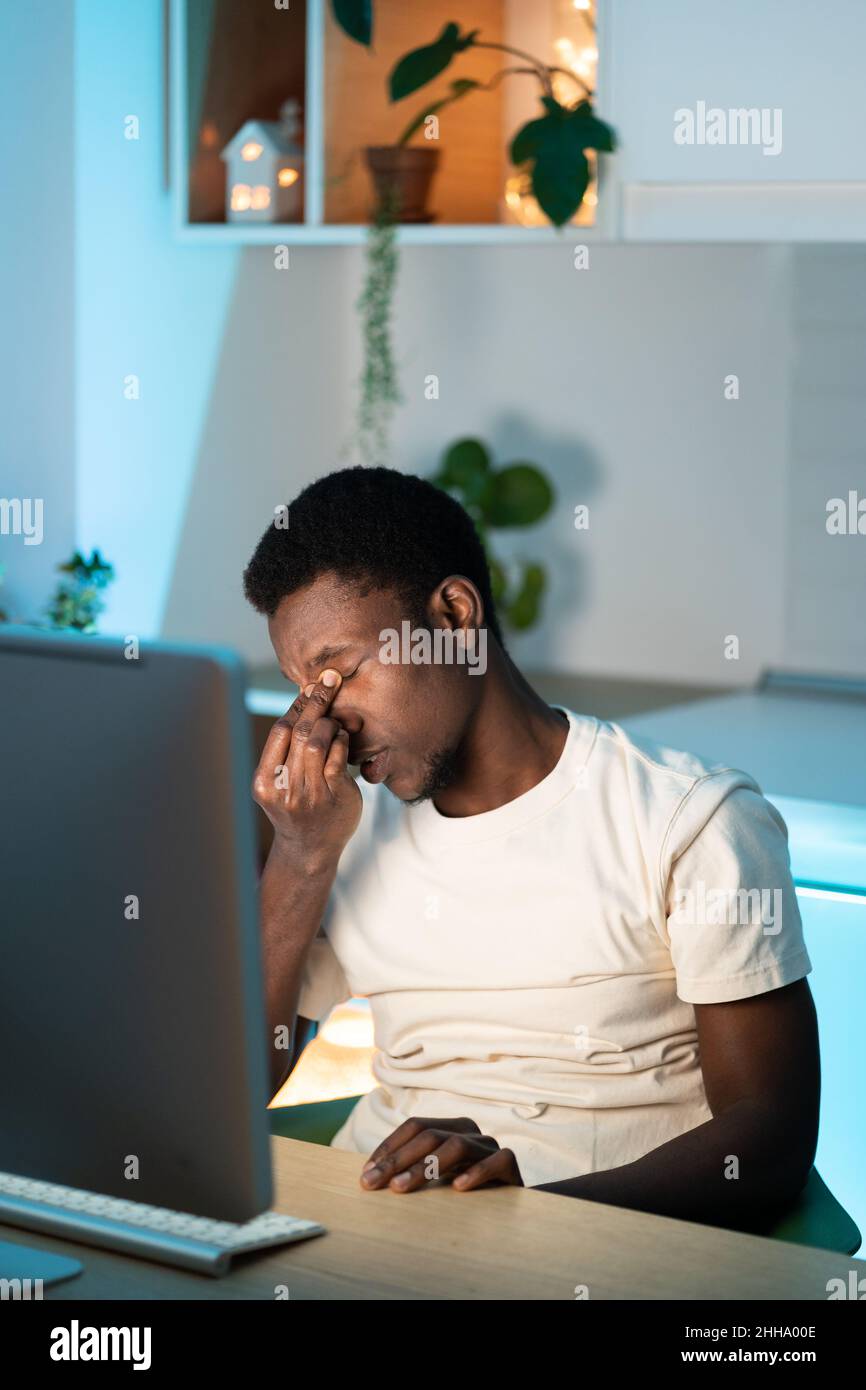 Tired freelance programmer man massage nose suffer from eyestrain ...