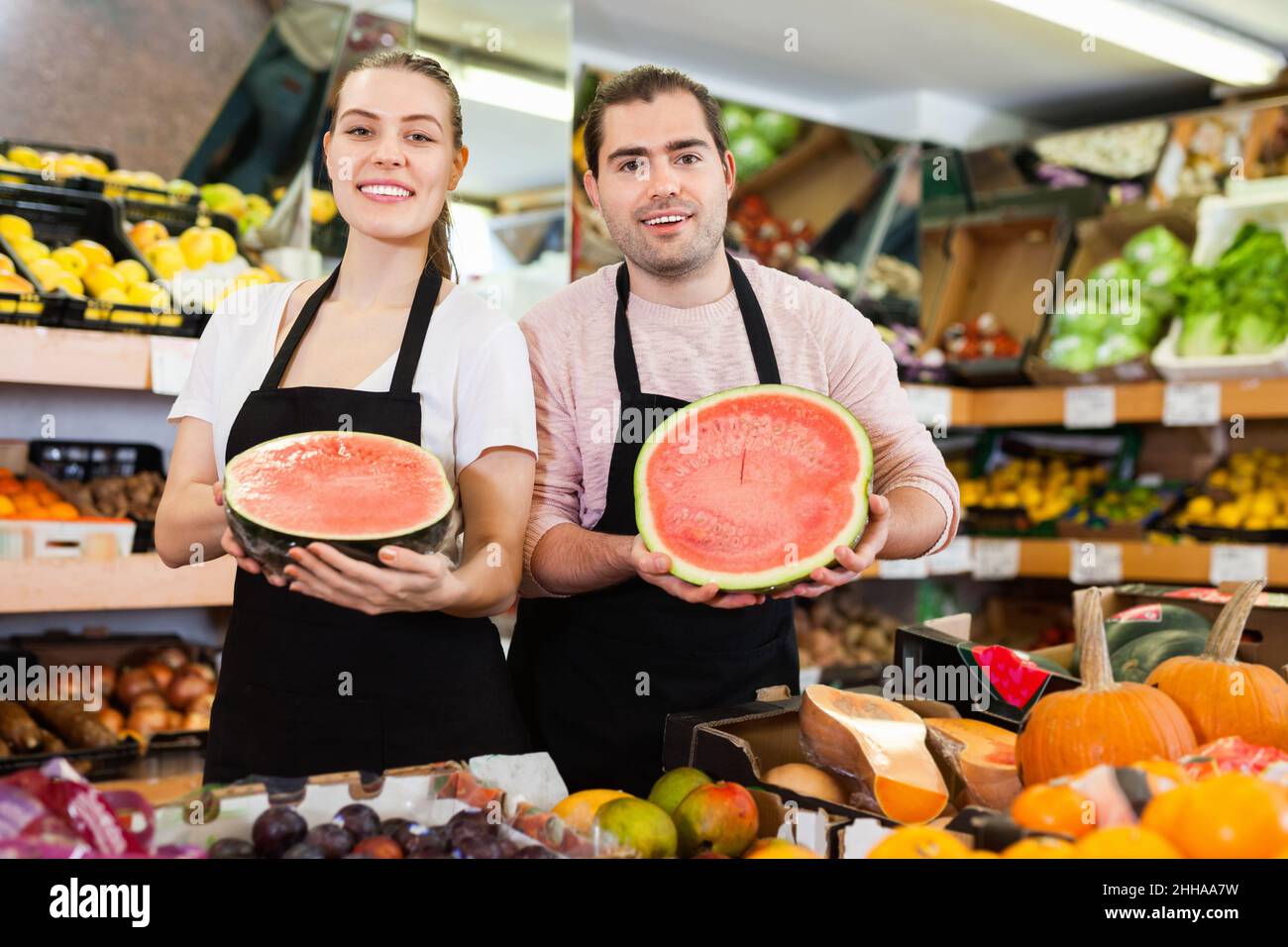 Young saleswoman and salesman holding half of watermelon in hands in ...