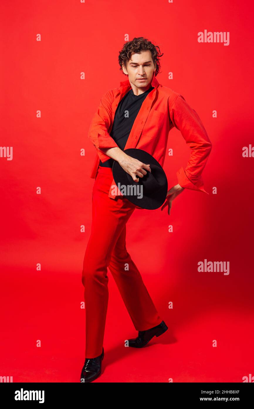 Portrait of a tall handsome man dressed in red shirt and black hat ...