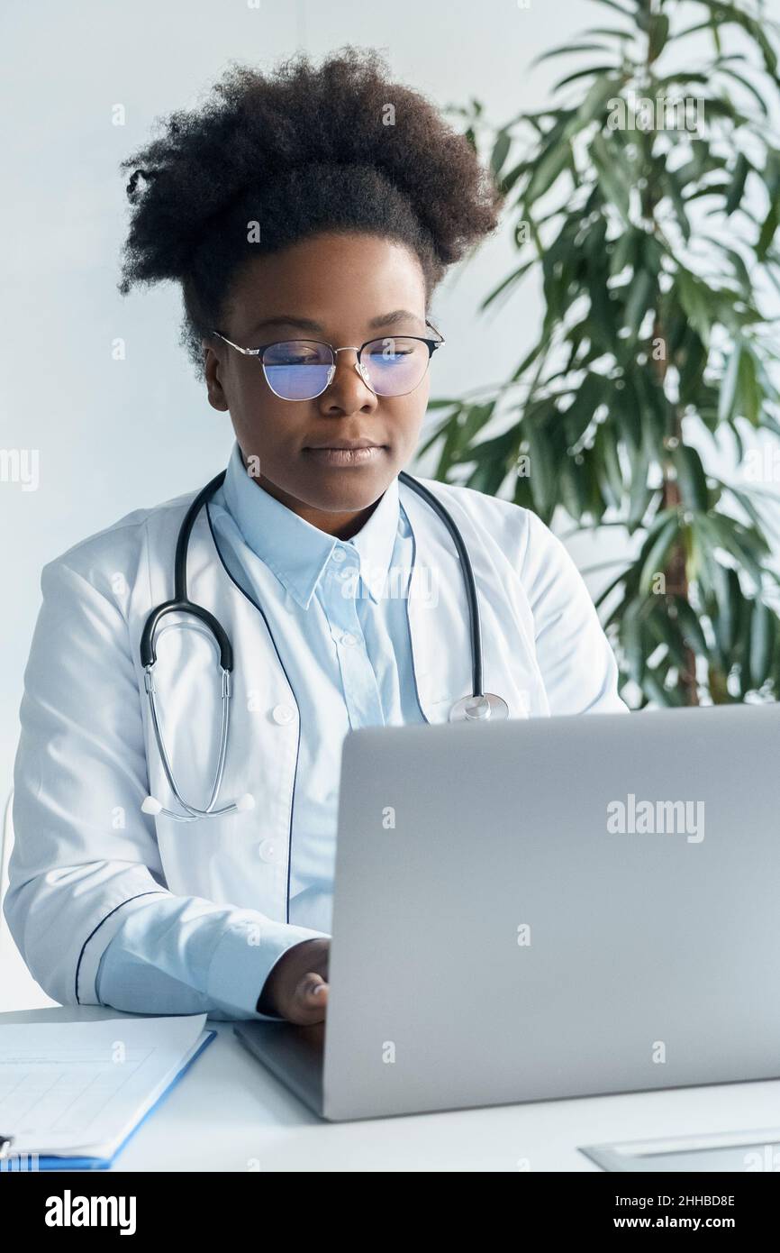 African American doctor using laptop computer in medical work or ...