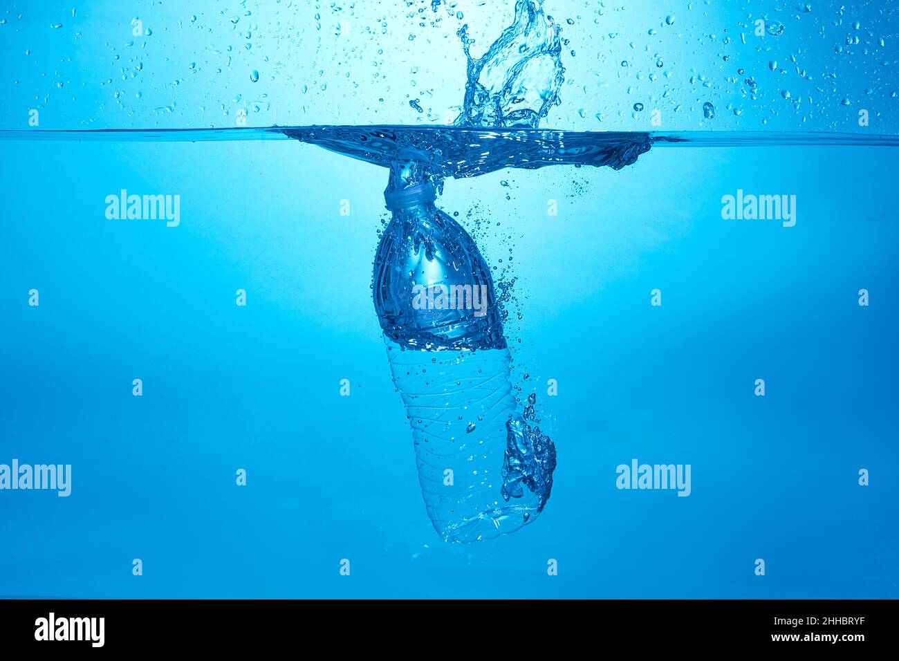Blue background with water bottle falling in and multiplle drops and ...