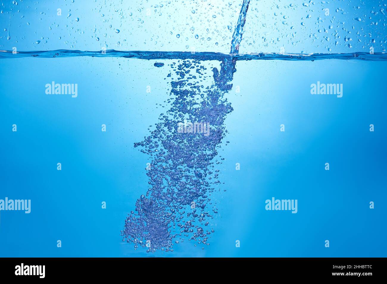 Blue background with water bottle falling in and multiplle drops and ...