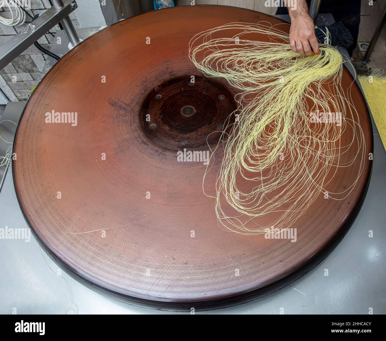 The making of Turkish dessert Kadayif pastry in display. Making kadayif ...