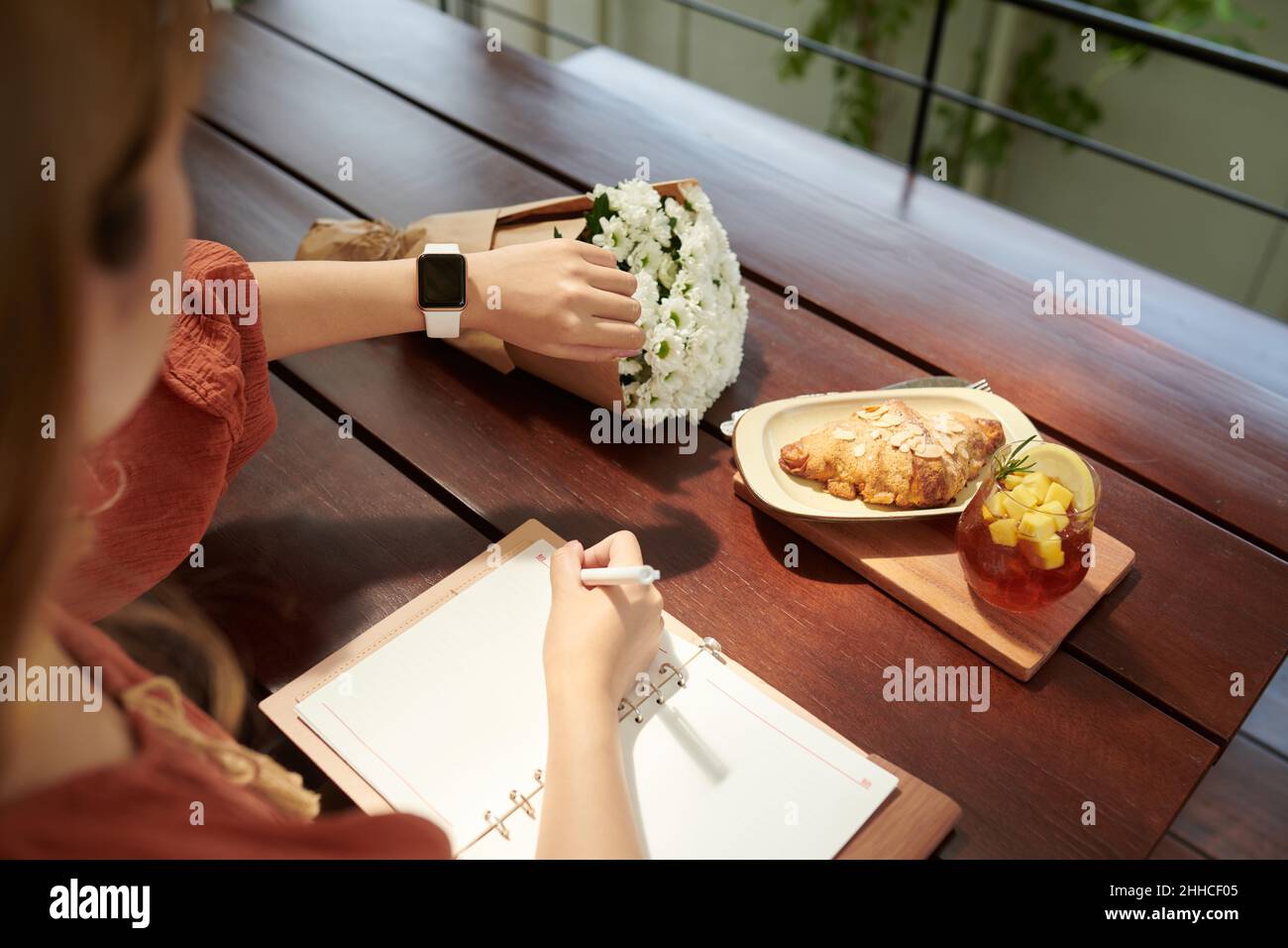 Hands of woman checking notification on her smartwatch and taking notes ...