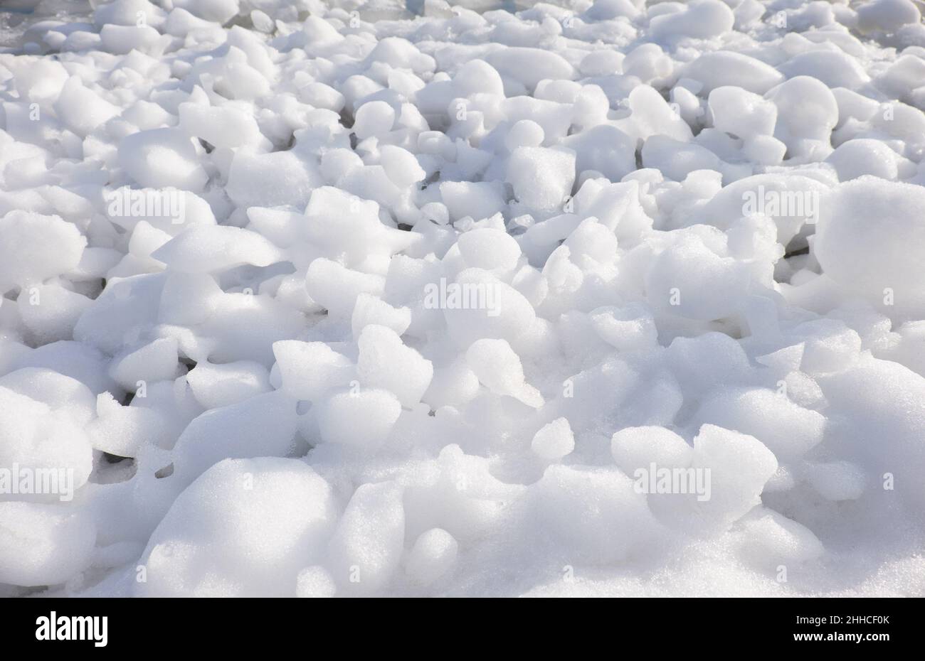 Lumps of snow and ice frazil on the surface of the freezing river water ...