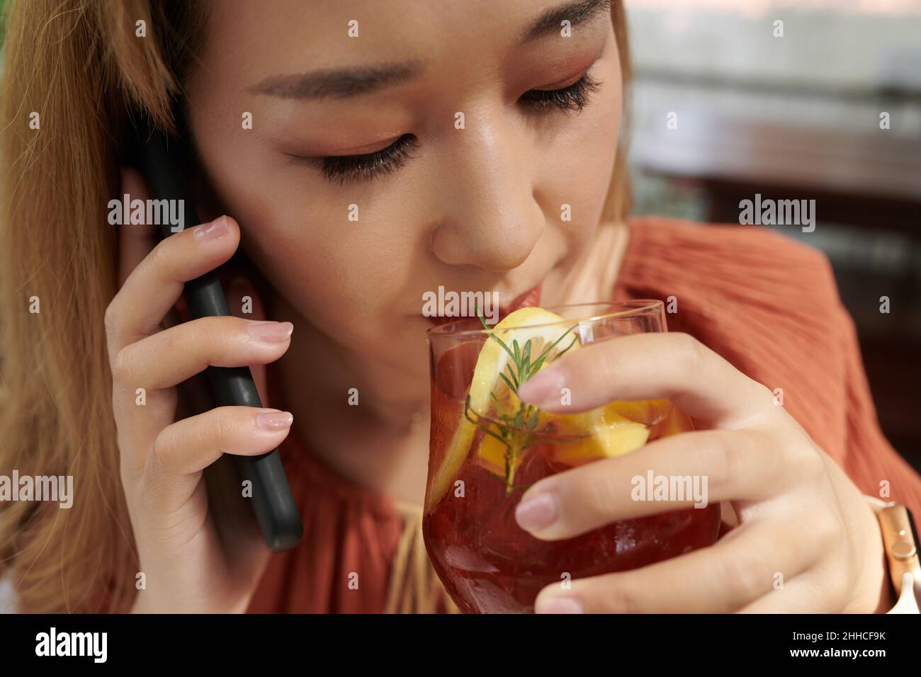 Closeup image of woman drinking iced tea and talking on phone with ...