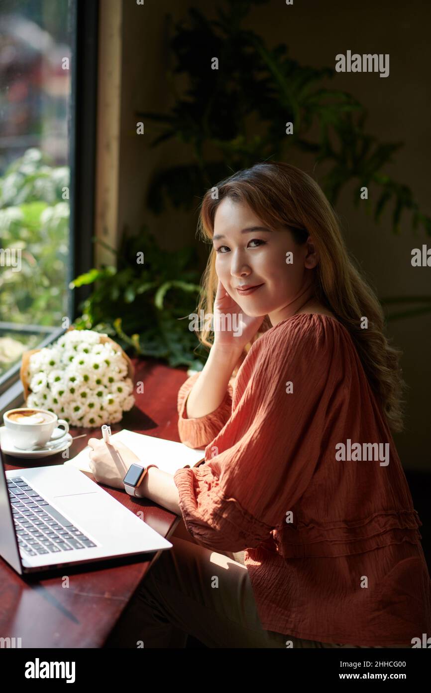 Portrait of young smiling university student sitting in coffeeshop and ...