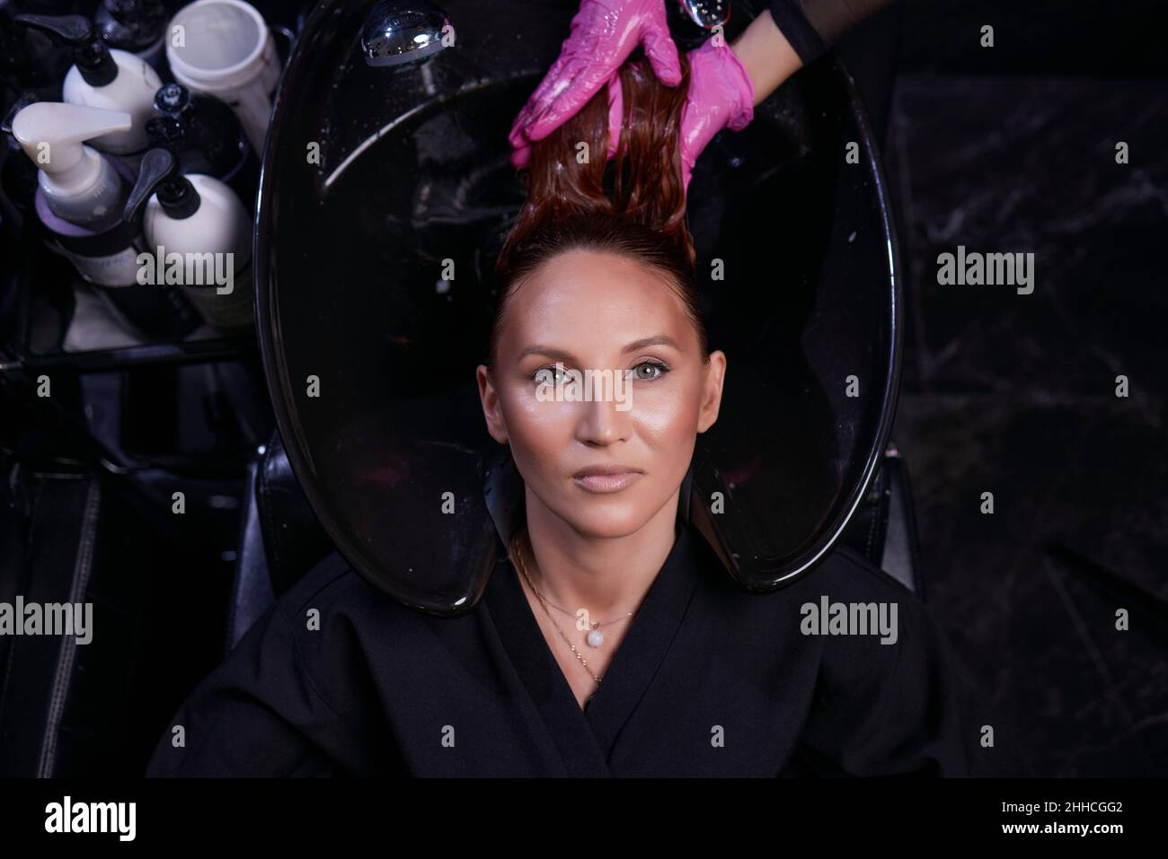 Hairdresser in beauty salon washes his client hair, before procedure of ...