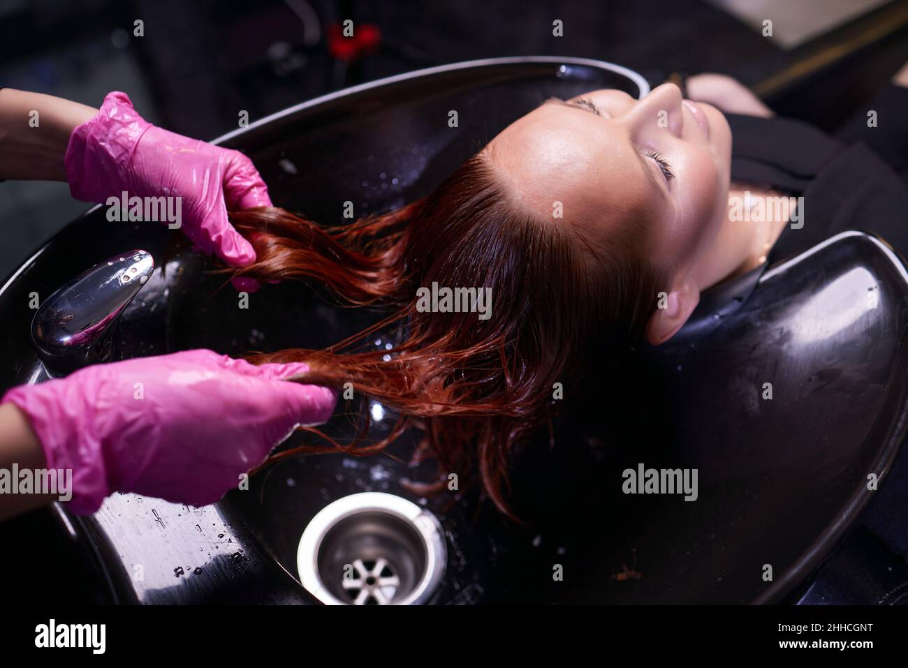 Hairdresser in beauty salon washes his client hair, before procedure of ...