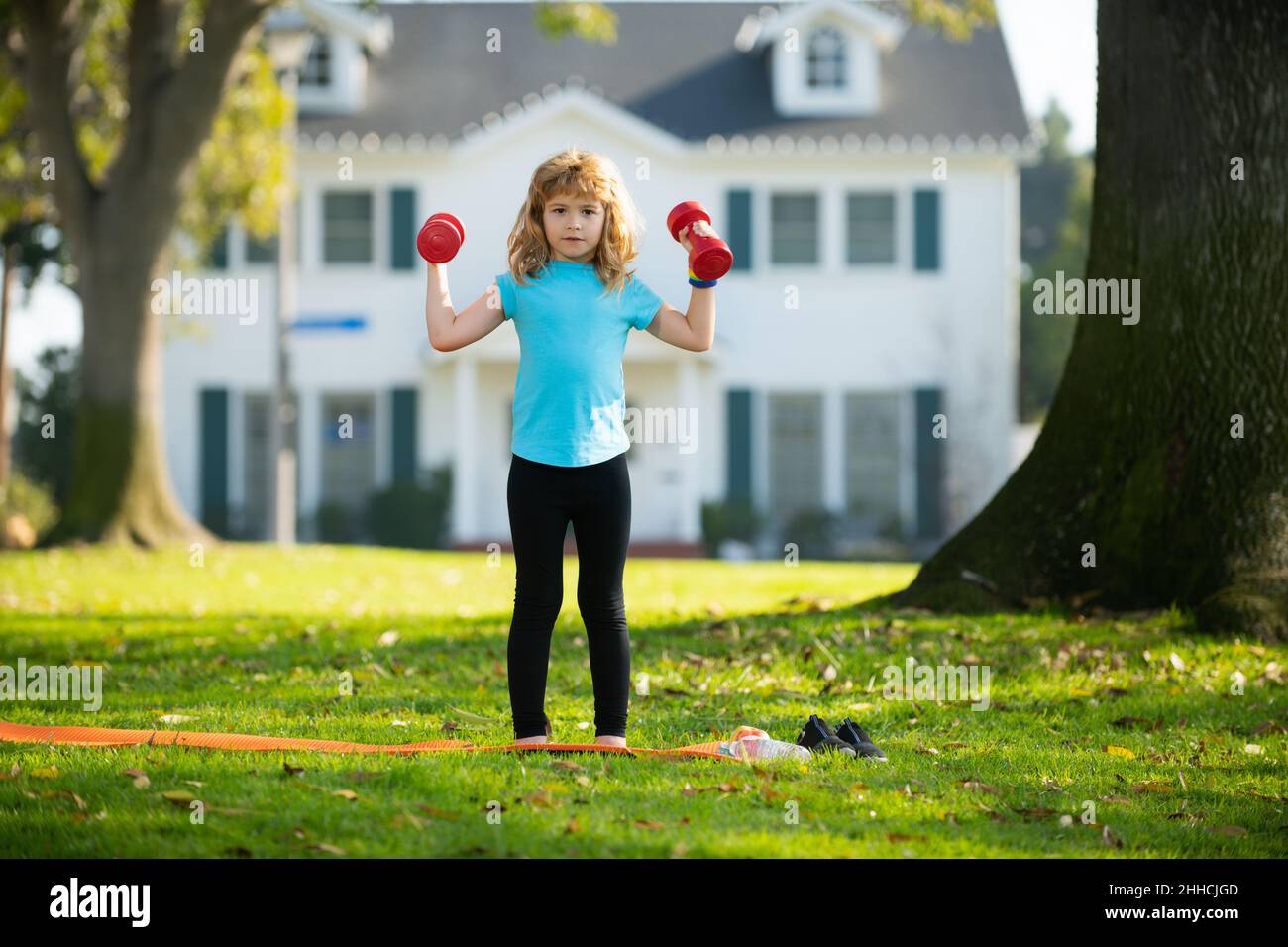 Child boy working out with dumbbells on park background. Kids sport ...