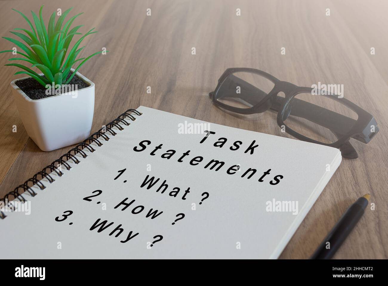 Text on white notepad with potted plan, glasses and a pen on wooden ...