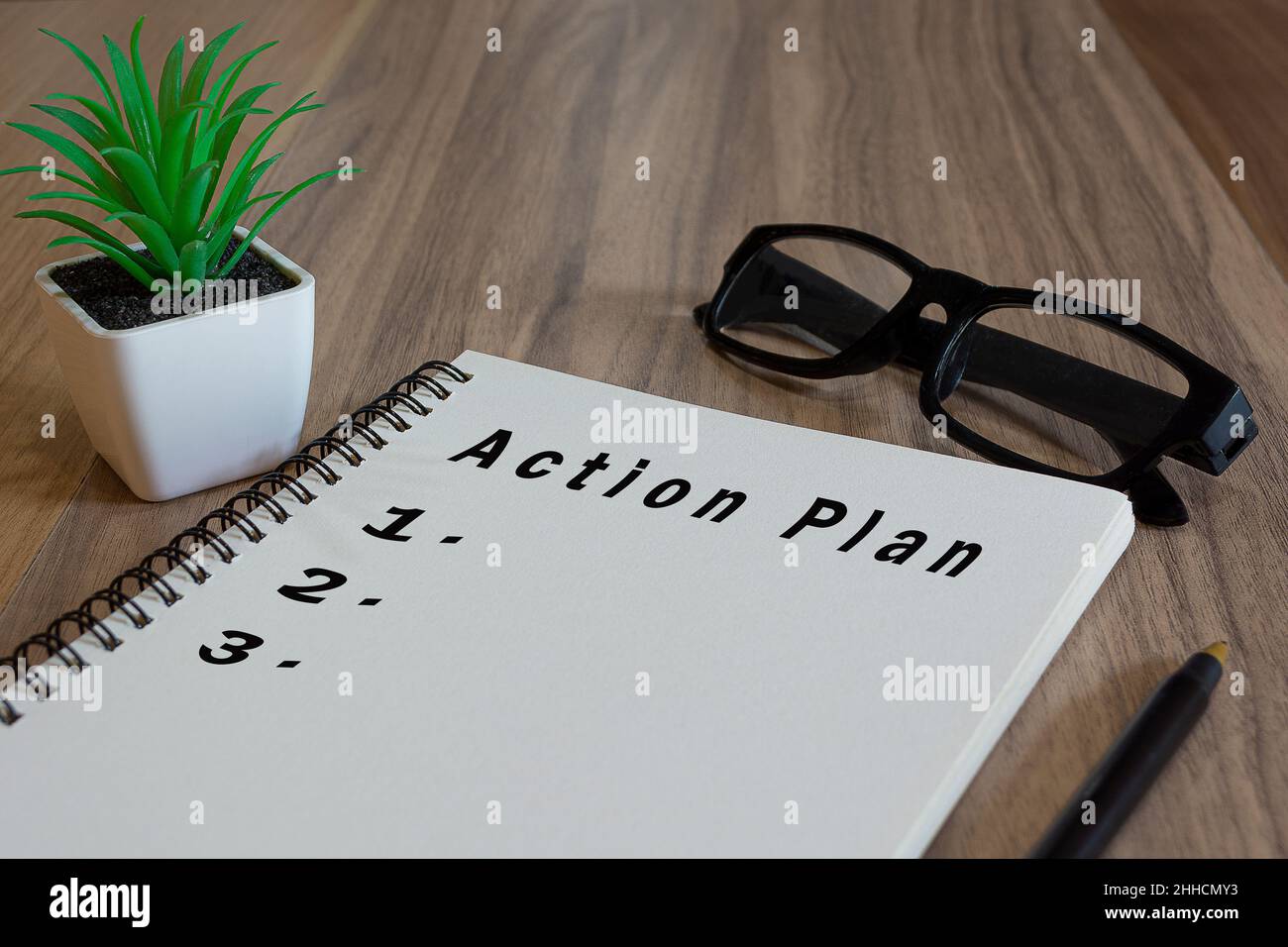 Action plan text on white notepad with potted plan, glasses and a pen ...