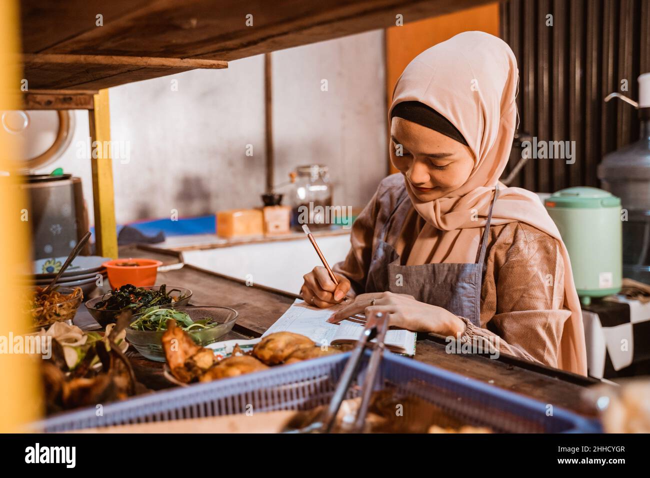 muslim food stall owner write note while working Stock Photo - Alamy