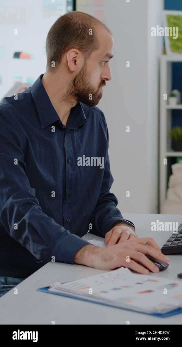 Corporate employee taking notes for project planning, using computer ...