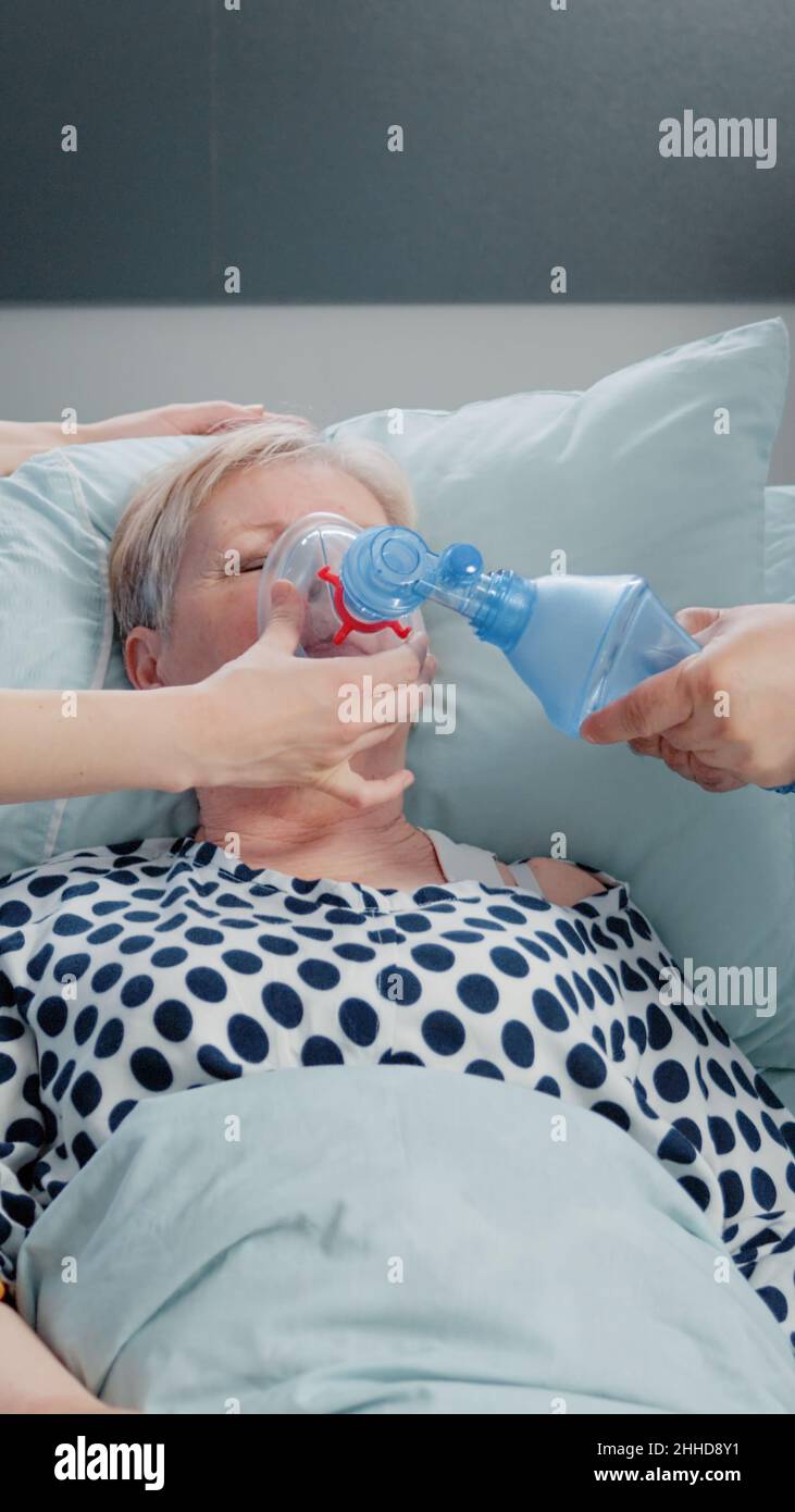 Doctor and nurse using oxygen tube for hyperventilating woman in bed ...