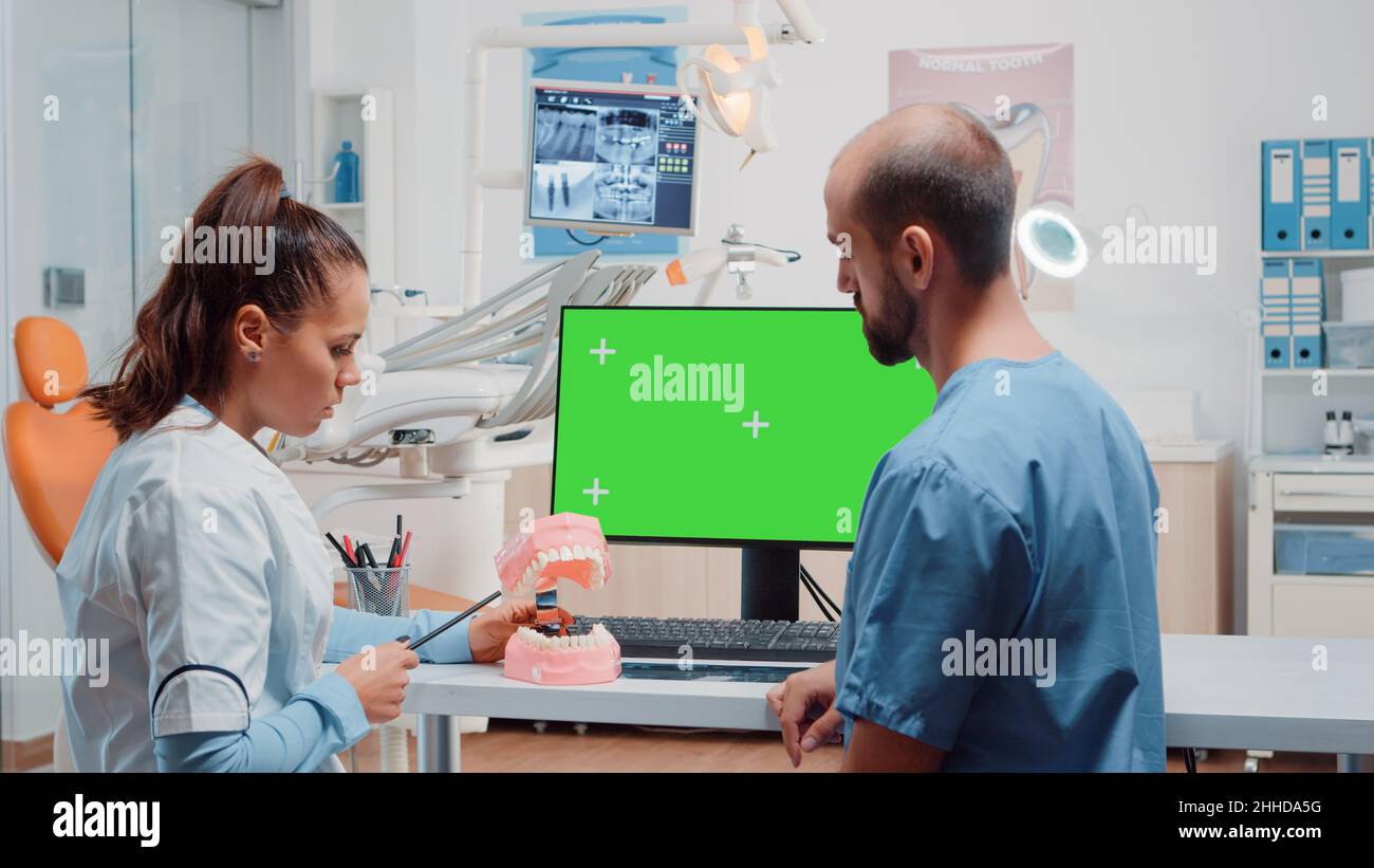 Nurse and dentist examining teeth layout using green screen on computer ...