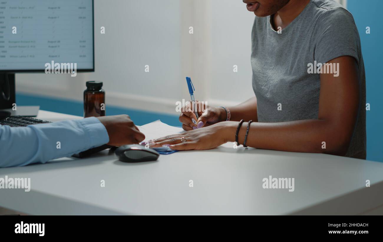 Close up of patient signing checkup papers for examination in cabinet ...