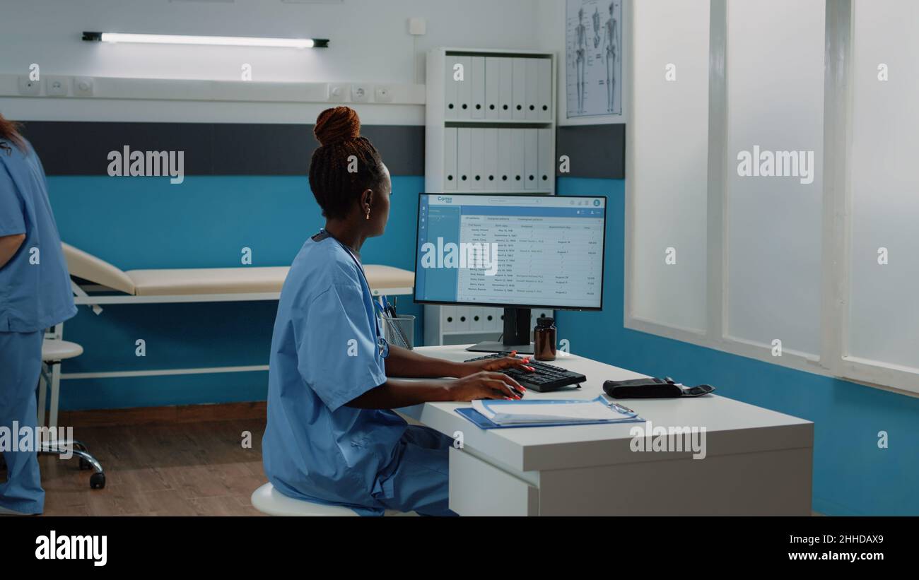 Medical assistant typing on computer keyboard in cabinet. Woman working ...