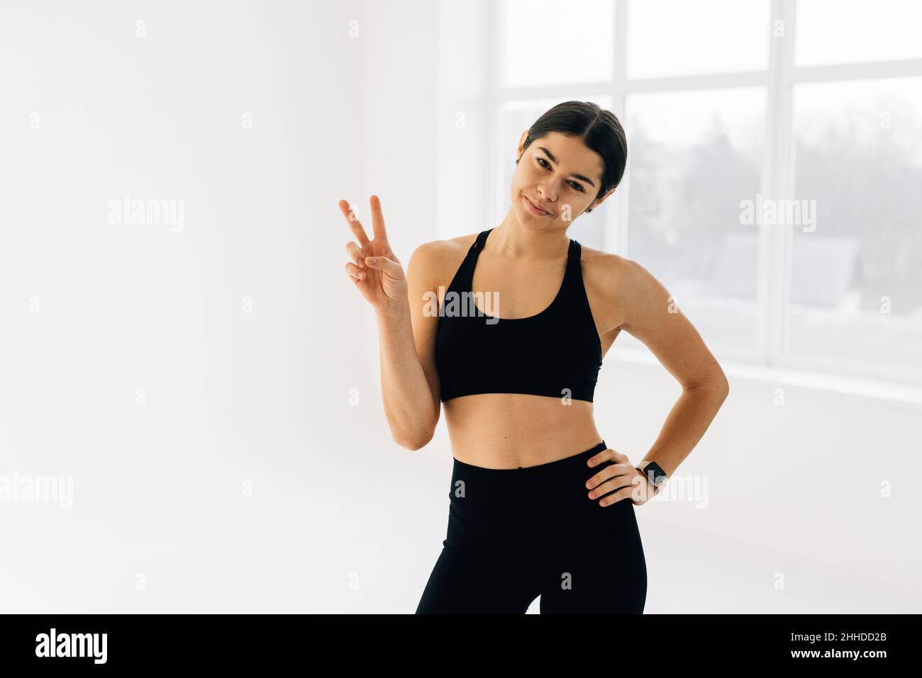 Fit and slim fitness girl showing peace sign and winking, workout in ...