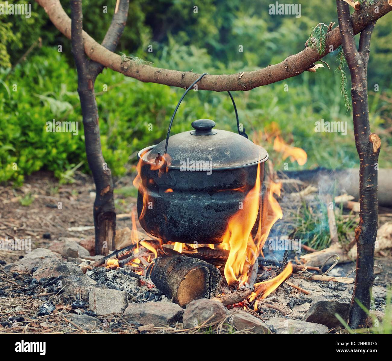 Cooking in field conditions, boiling pot at the campfire on picnic ...
