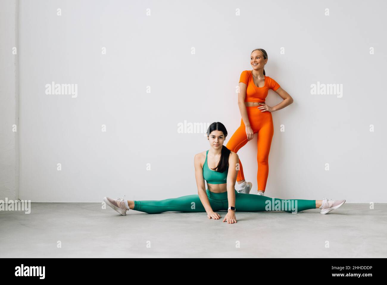 Two sporty women doing side leg raise exercise with stretch band lying ...
