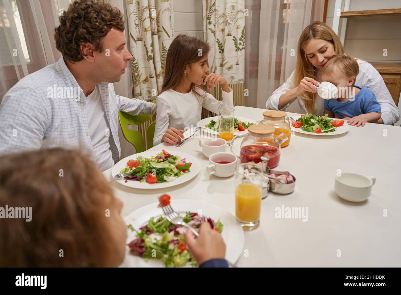 Cheerful female person giving tea to her son Stock Photo - Alamy