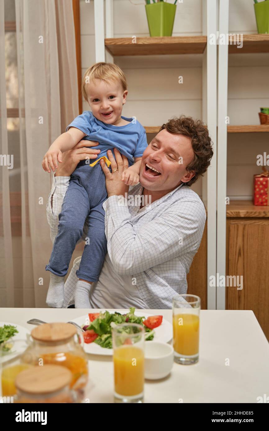 Positive delighted man playing with his son Stock Photo - Alamy