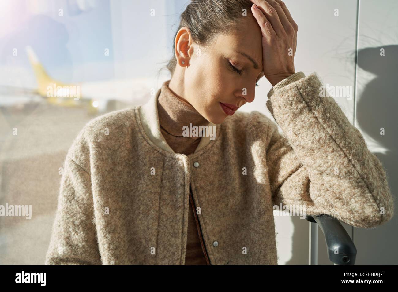 Woman in trouble grabbing her head in airport Stock Photo - Alamy