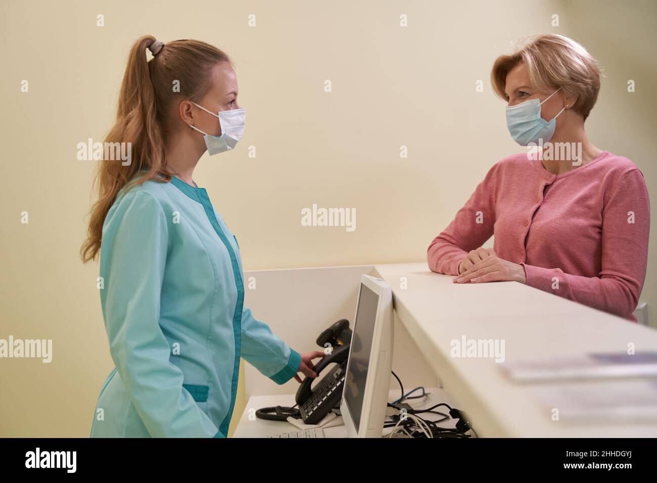 Pleased blonde female person talking to receptionist Stock Photo - Alamy