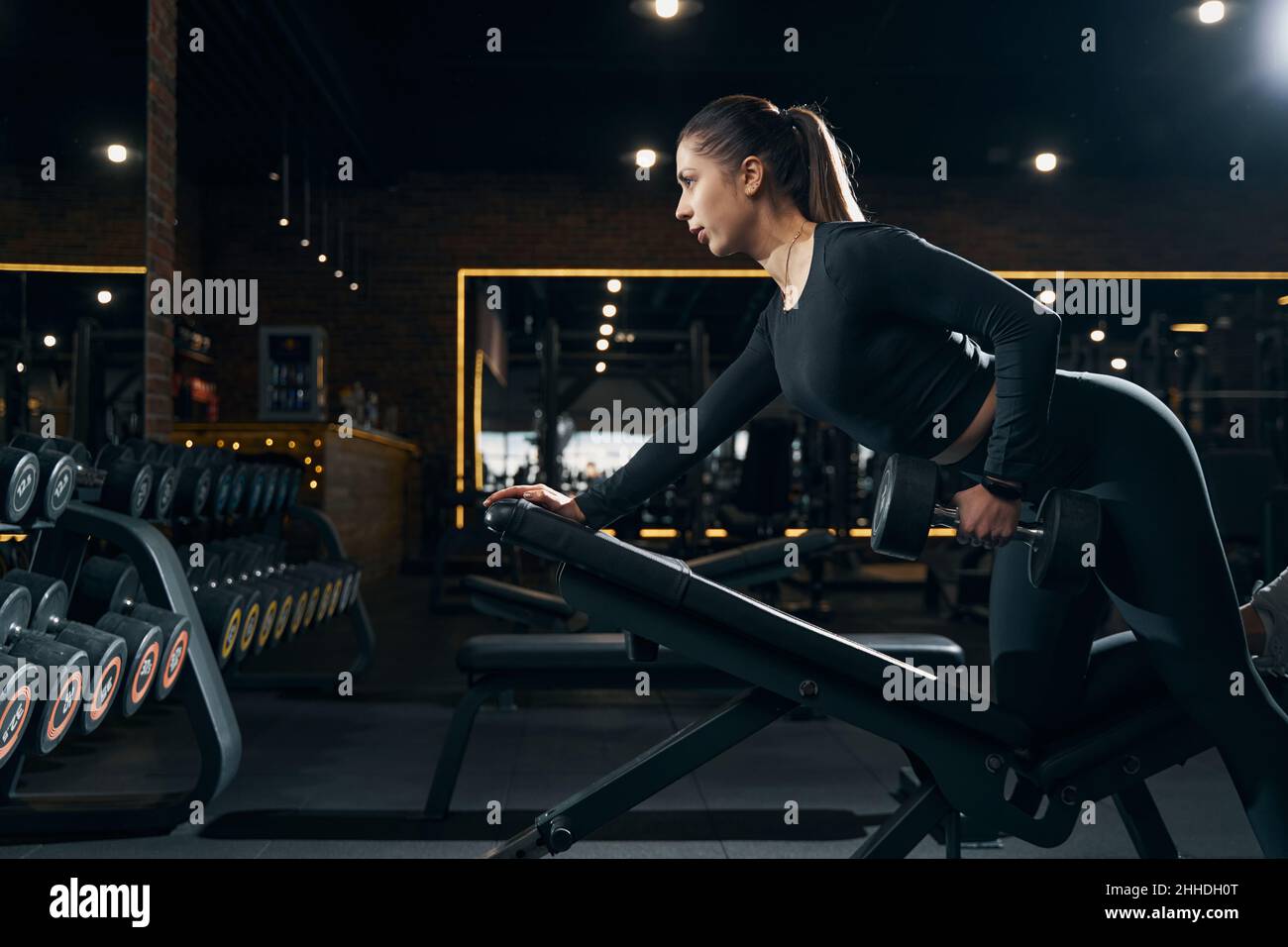 Fit young woman performing single-arm dumbbell exercise Stock Photo - Alamy