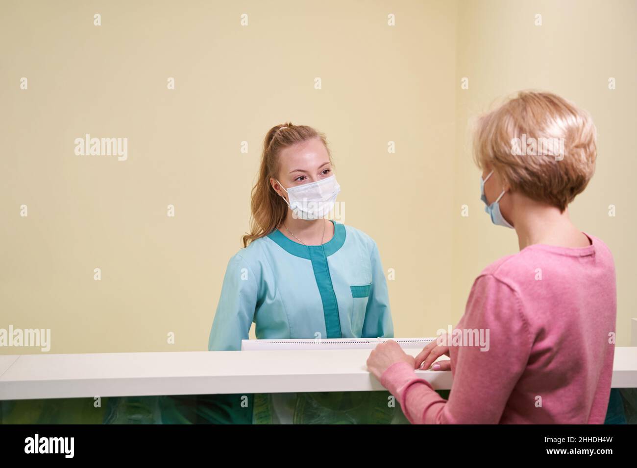 Two friendly females standing at the reception desk Stock Photo - Alamy